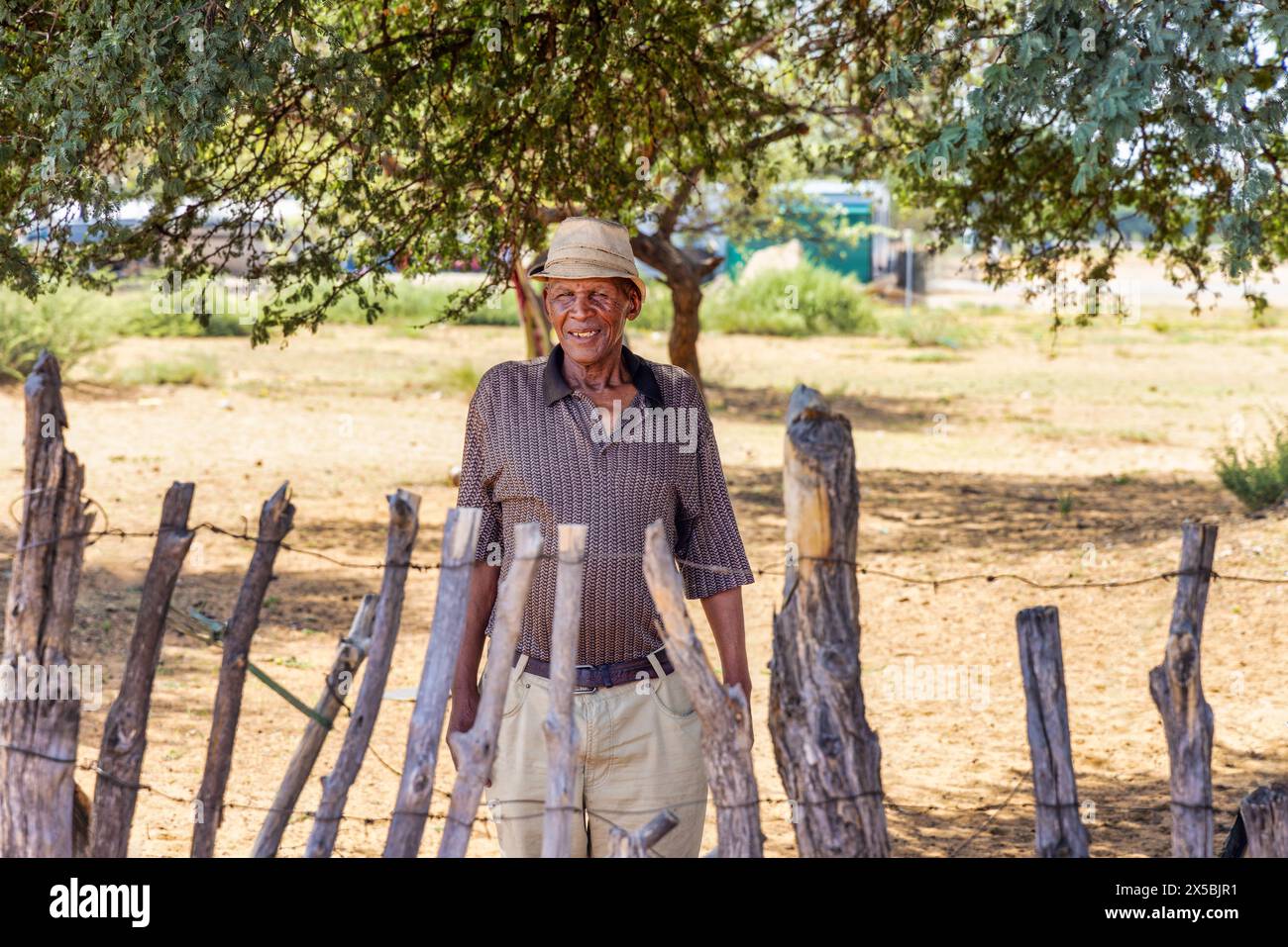 African village, single old man with a hat behind the wooden fence ...