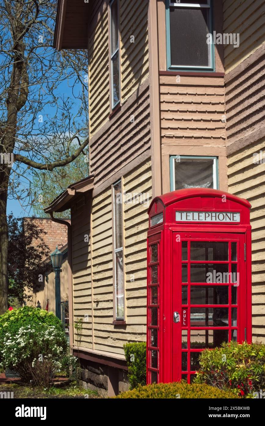 A vintage British-style phone booth stands next to an old house in a ...
