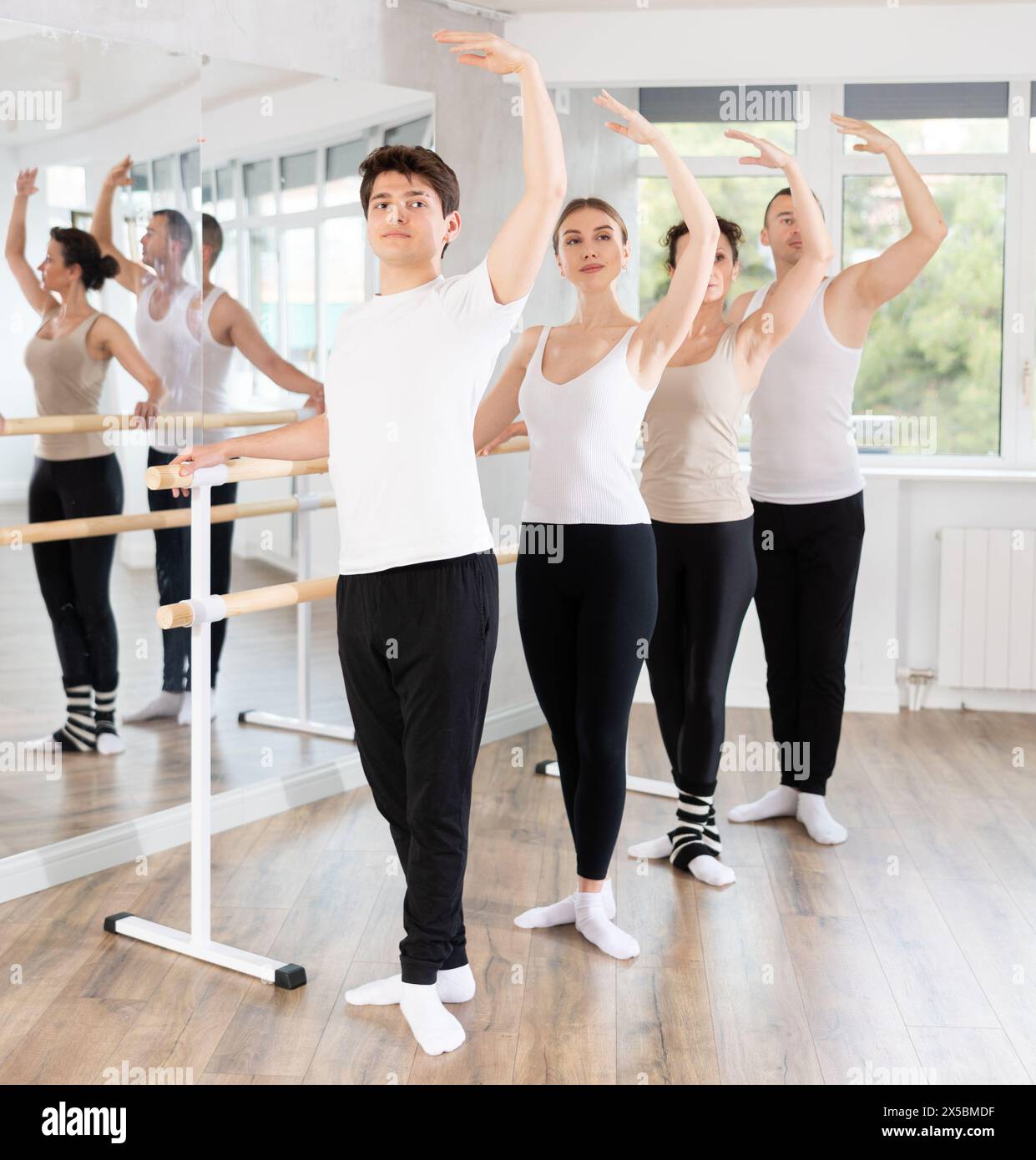 Guy performing third position at barre during group ballet class Stock ...