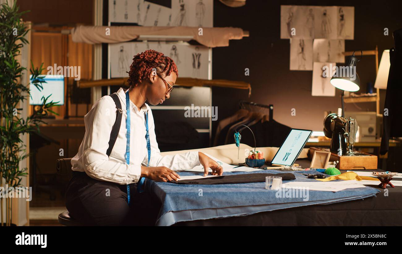 Female tailor designing clothes using sketches on tablet and papers ...