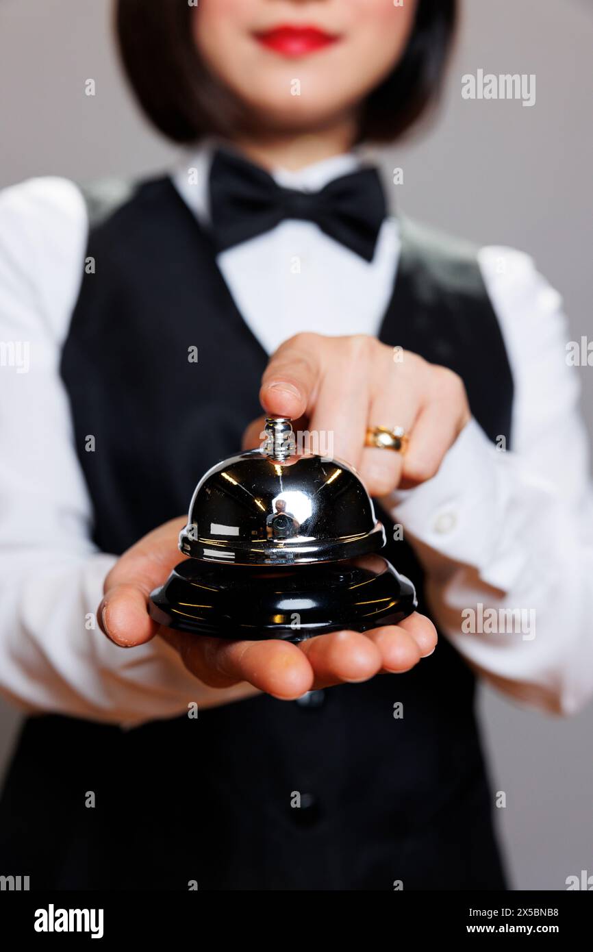 Waitress wearing professional uniform pressing hospitality bell with ...