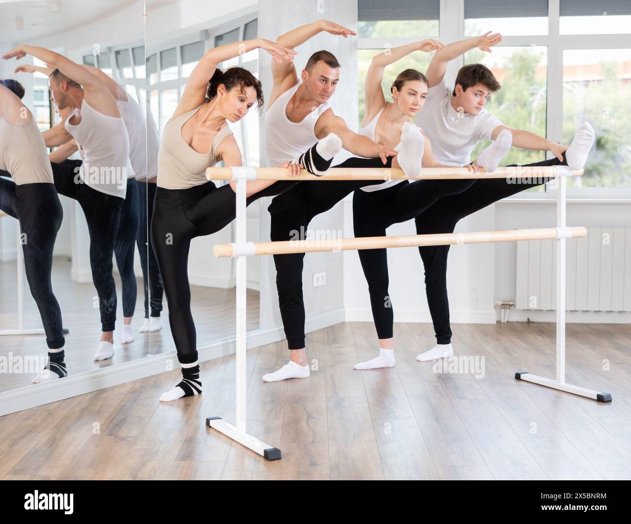 Group of young female and male ballet dancers learn grand batman ...