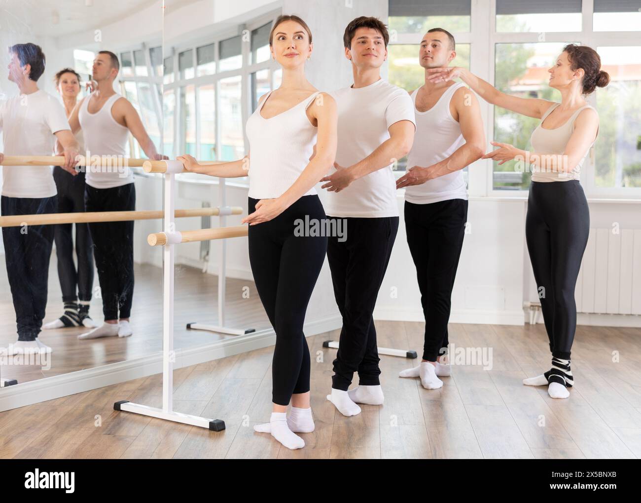 Experience female ballet instructor adjusting students form. Diligent ...