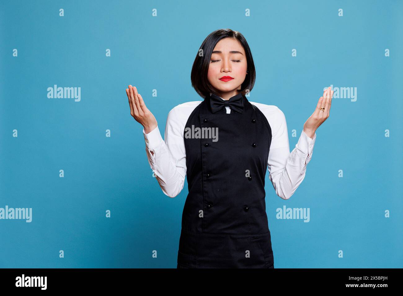 Young attractive asian waitress with closed eyes practicing breathing ...