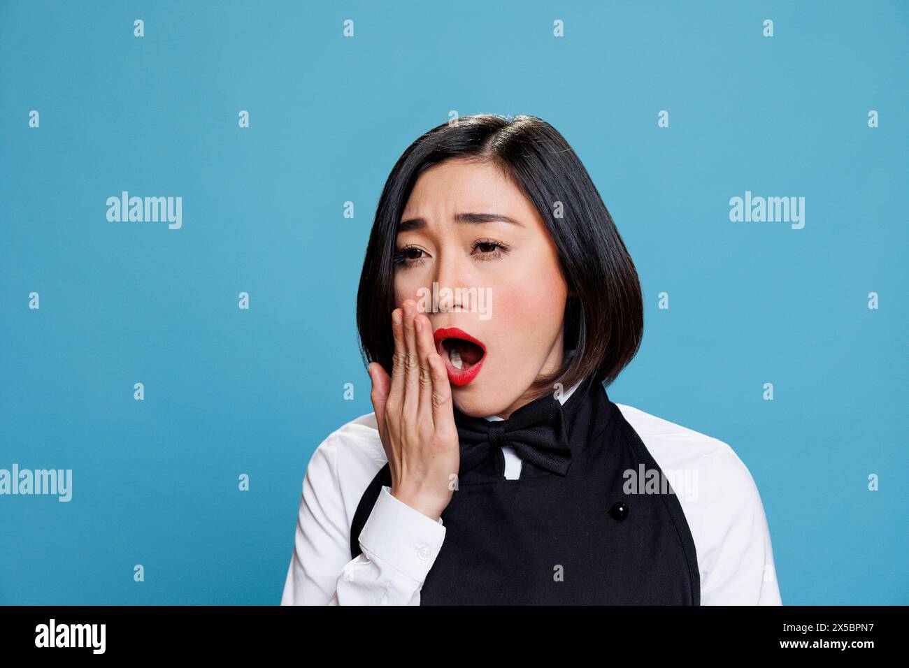 Sleepy young aisan woman receptionist yawning and covering mouth with ...