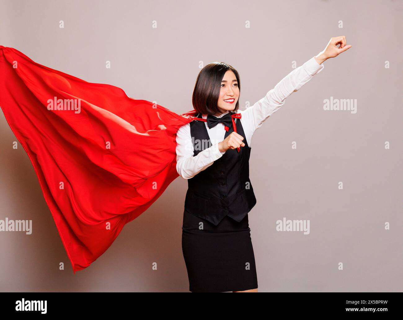 Smiling asian woman receptionist wearing uniform and superman cloak ...