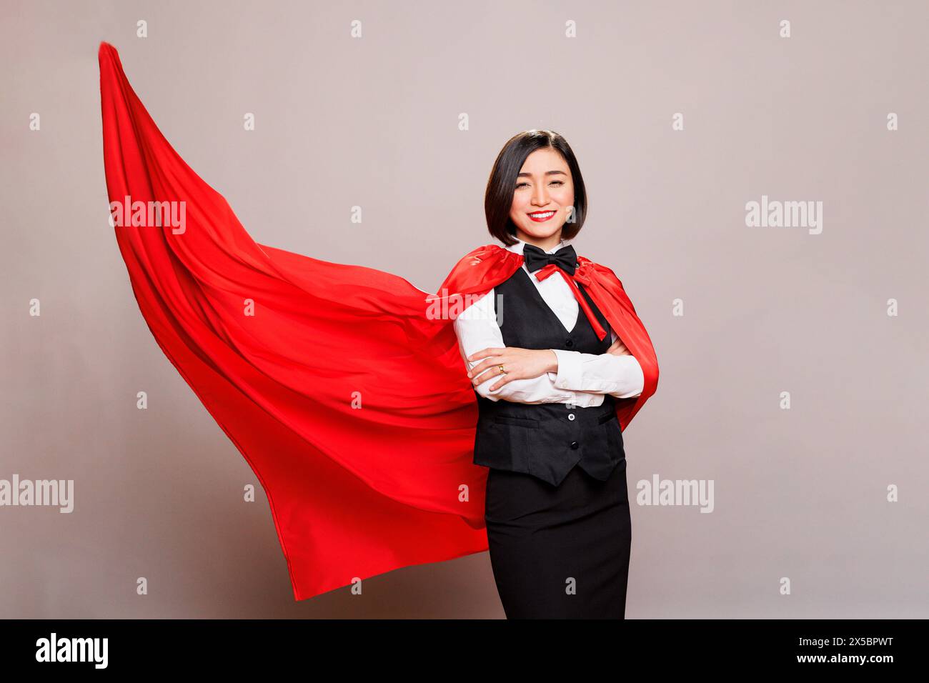 Smiling receptionist standing with folded hands in fluttering ...