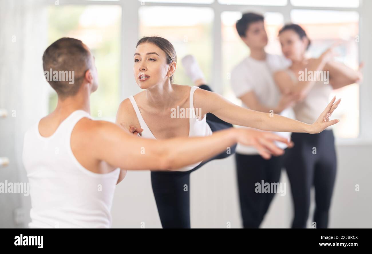 Portrait of positive young man and female partner training ballet pose ...