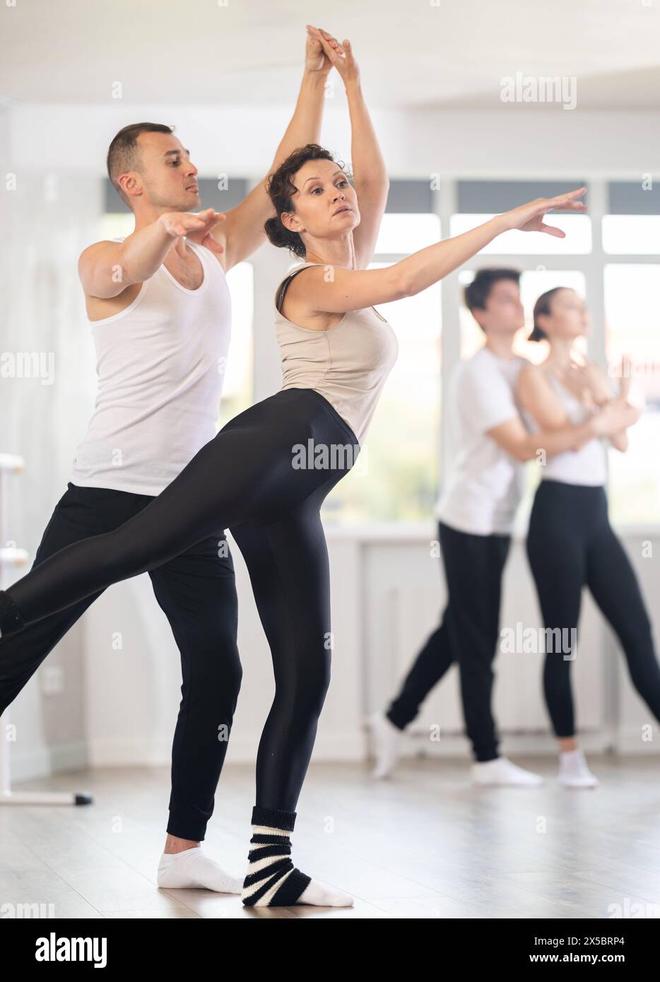 Pretty female ballerina and male partner practicing ballet arabesque ...