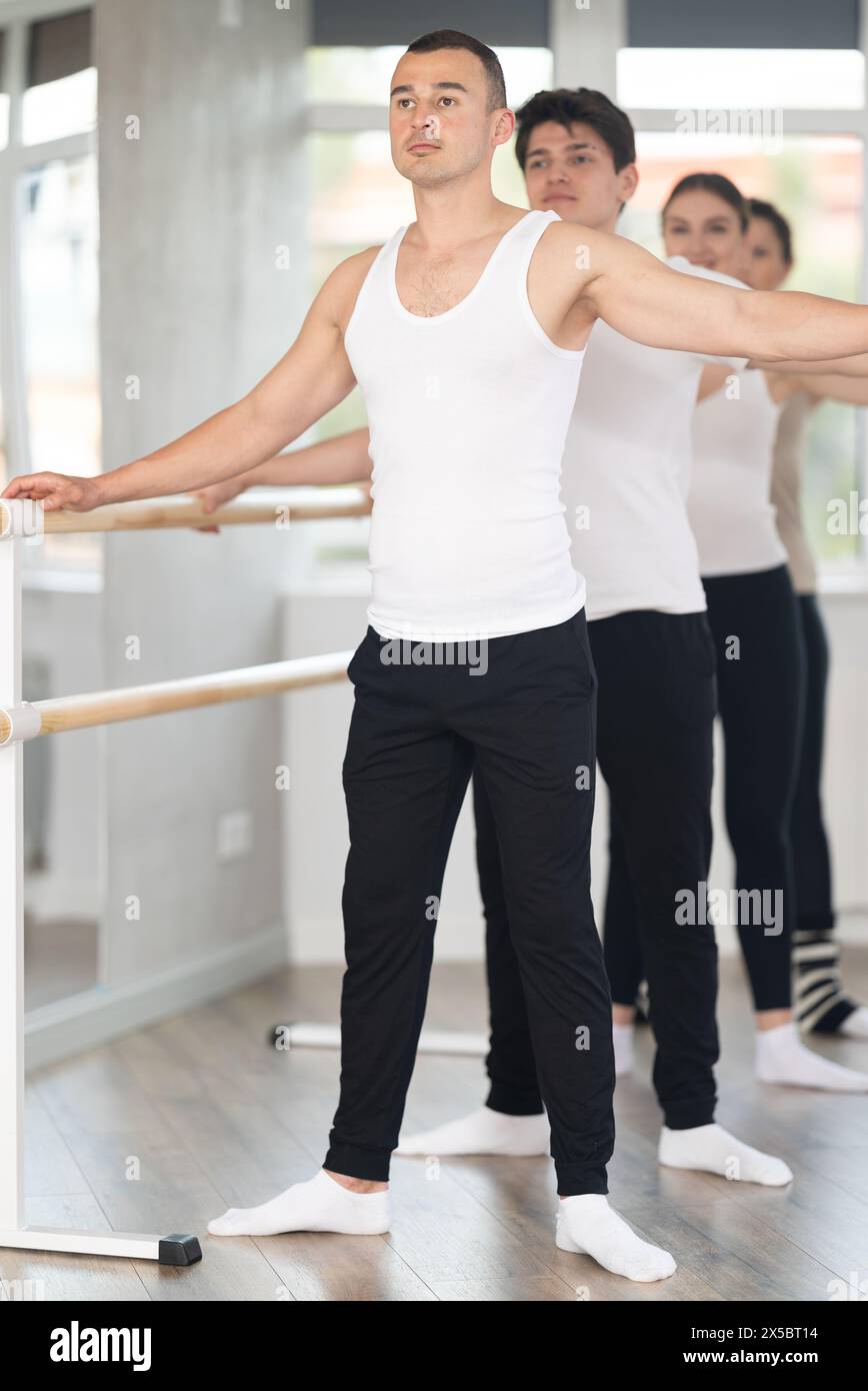 Man mastering second position at barre at group ballet class Stock ...