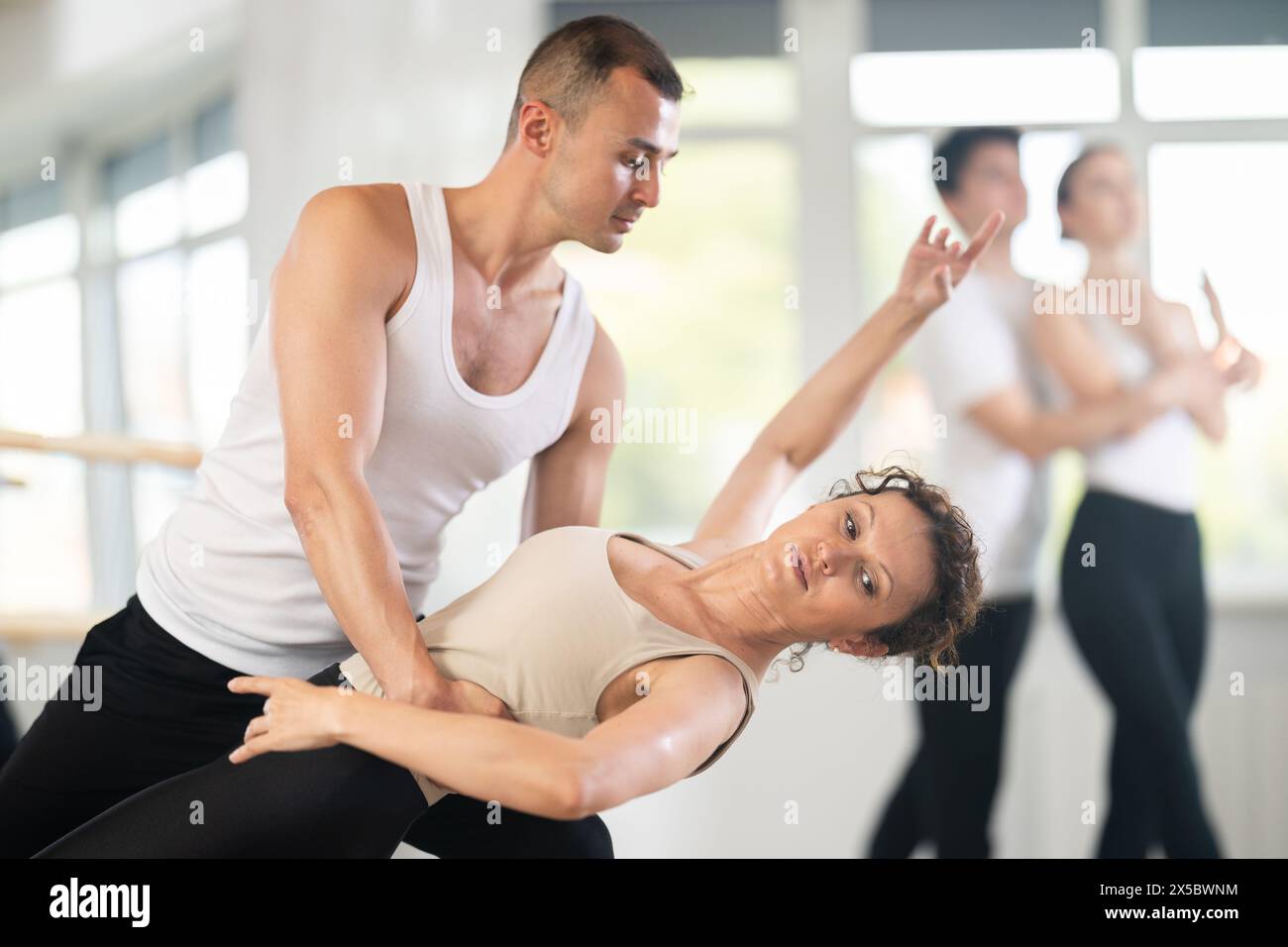 Portrait of positive young man and female partner training ballet pose ...
