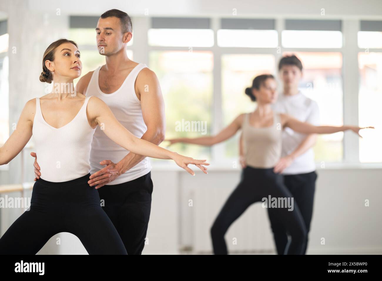 Ballet partners mastering paired technique at group class in studio ...