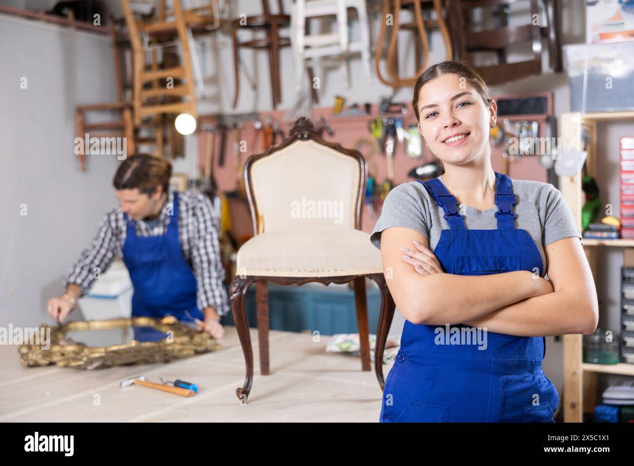 Cheerful young female furniture restorer showing his vintage furniture ...