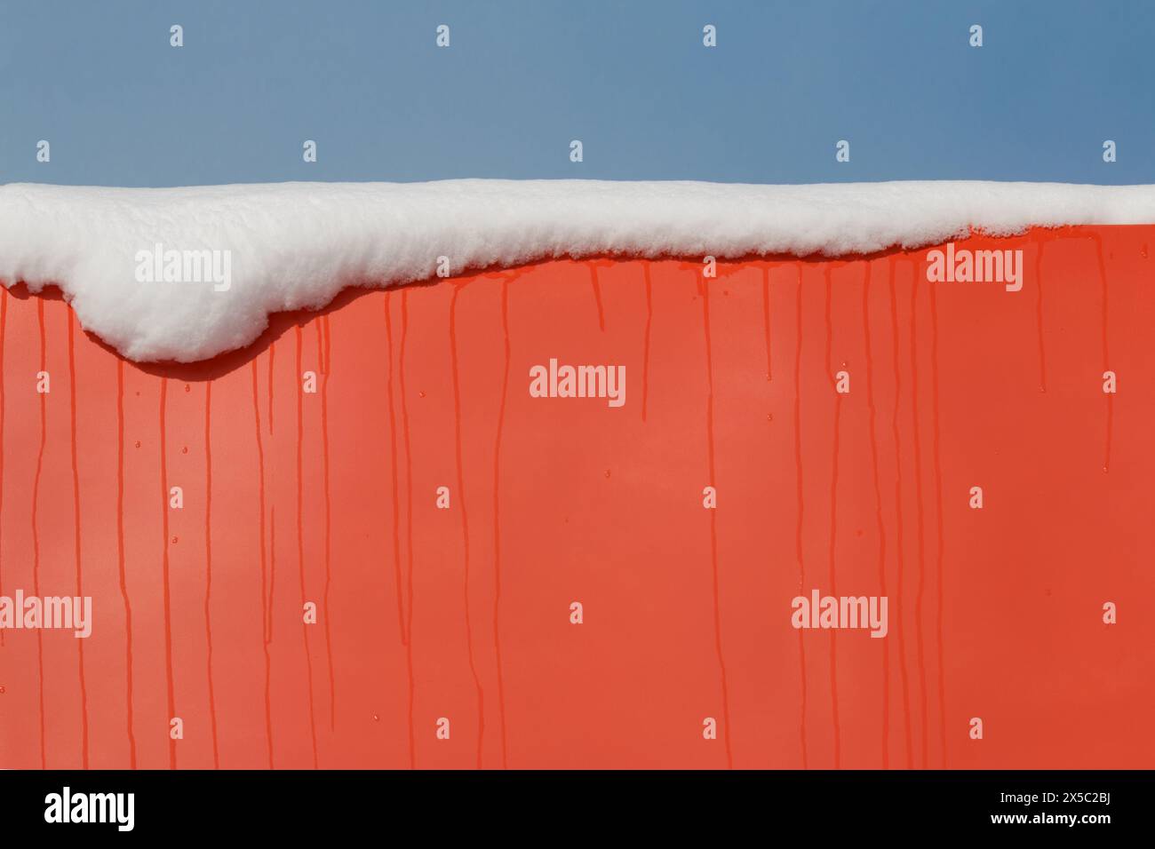 Melting snow dripping water from top of bright red metal wall Stock ...