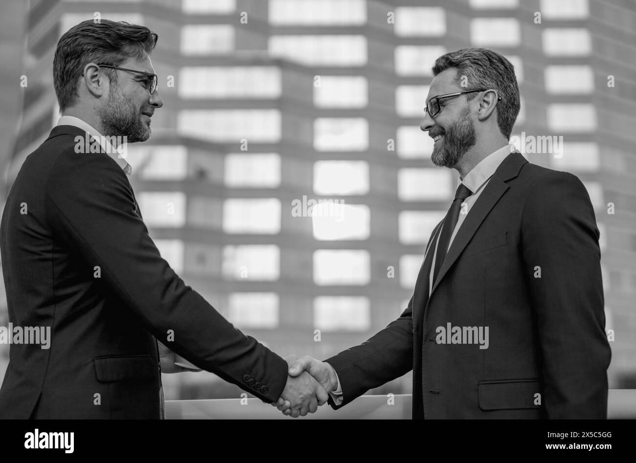 Two businessmen shaking hands on city street. Business men in suit ...