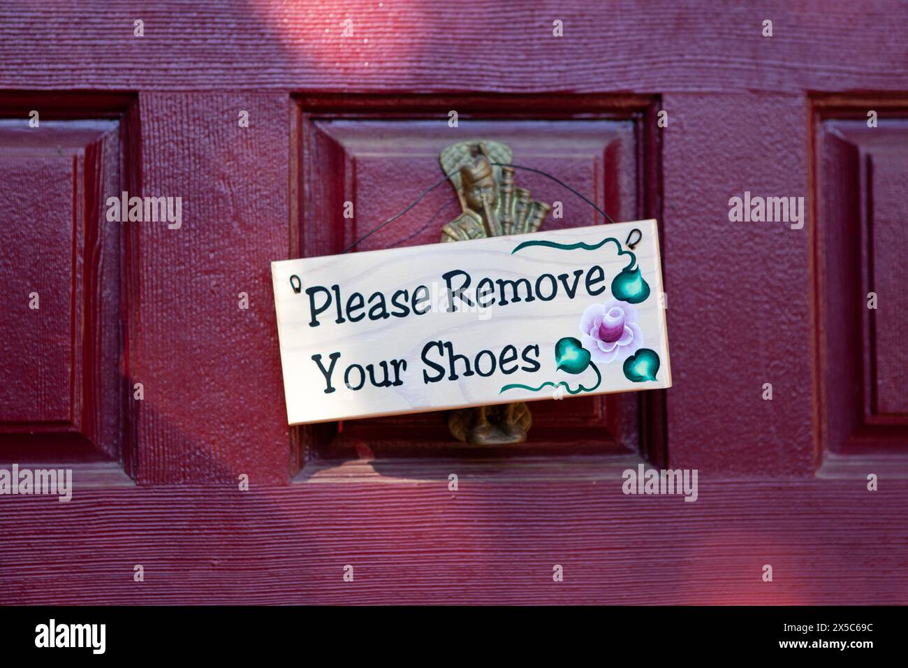 A sign hangs on a front door advising guests to remove their shoes ...