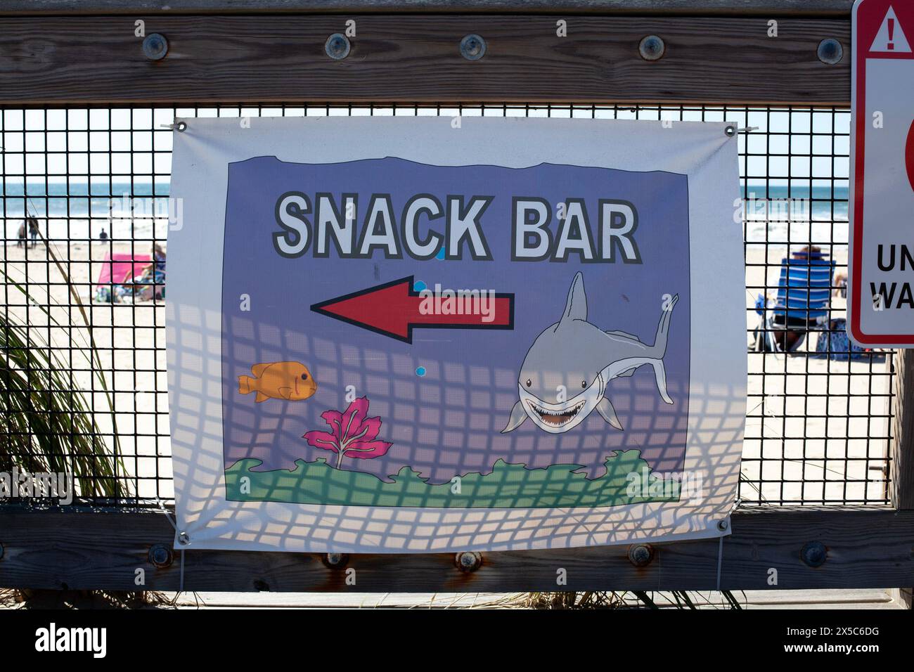 A sign points visitors in the direction of the snack bar at a beach ...