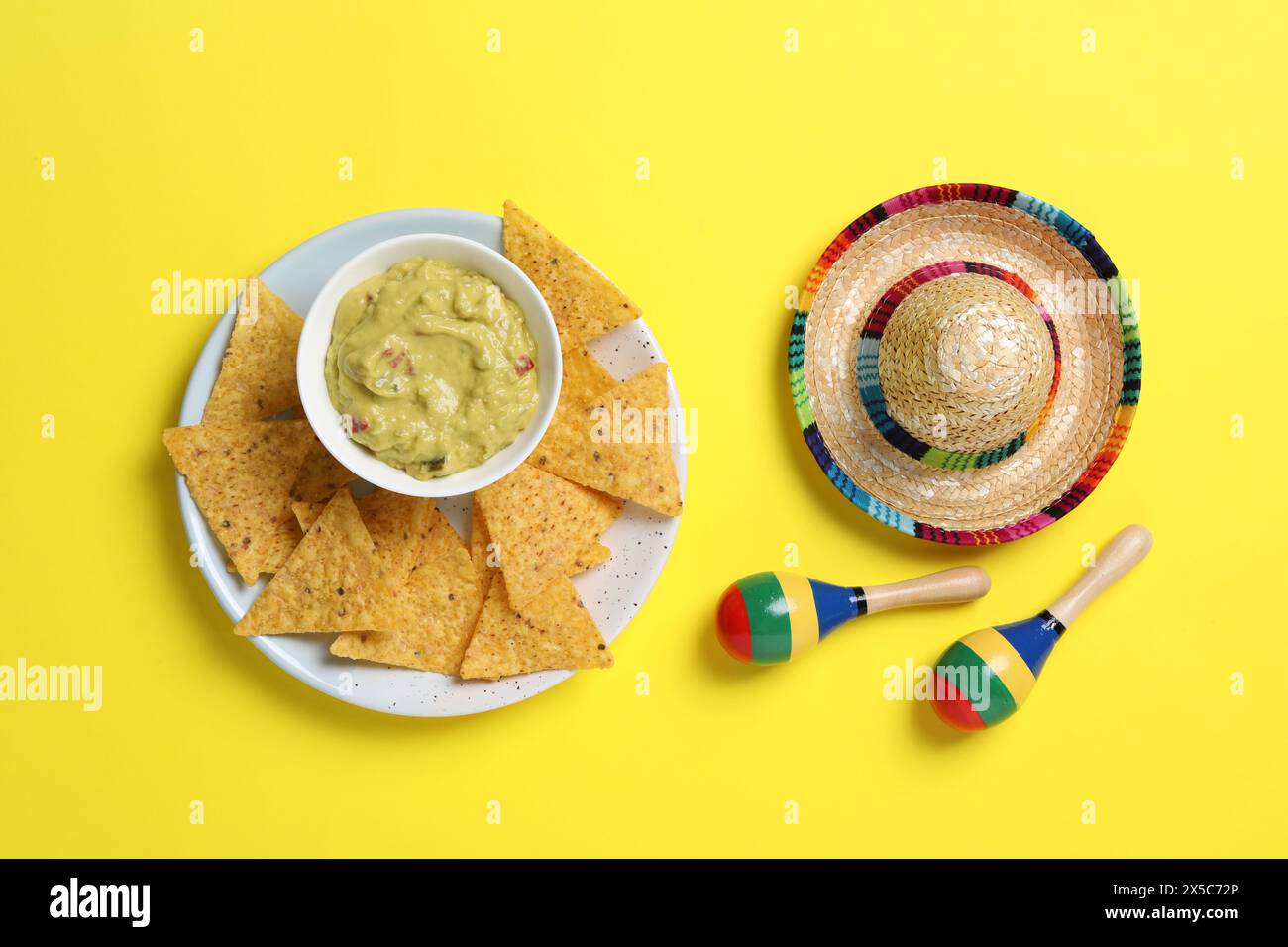 Mexican sombrero hat, nachos chips, guacamole and maracas on yellow ...