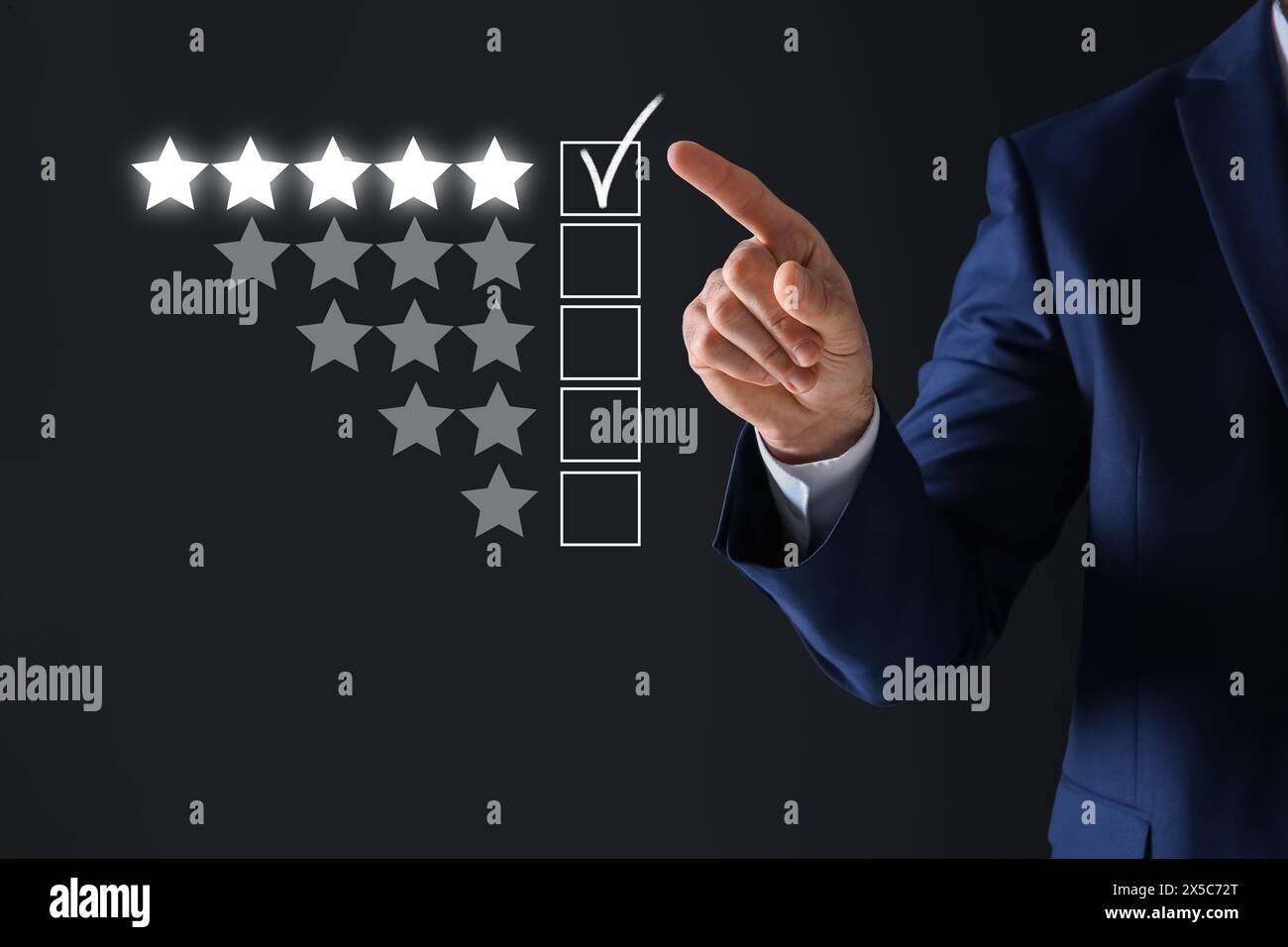 Man choosing five stars on virtual screen against black background ...