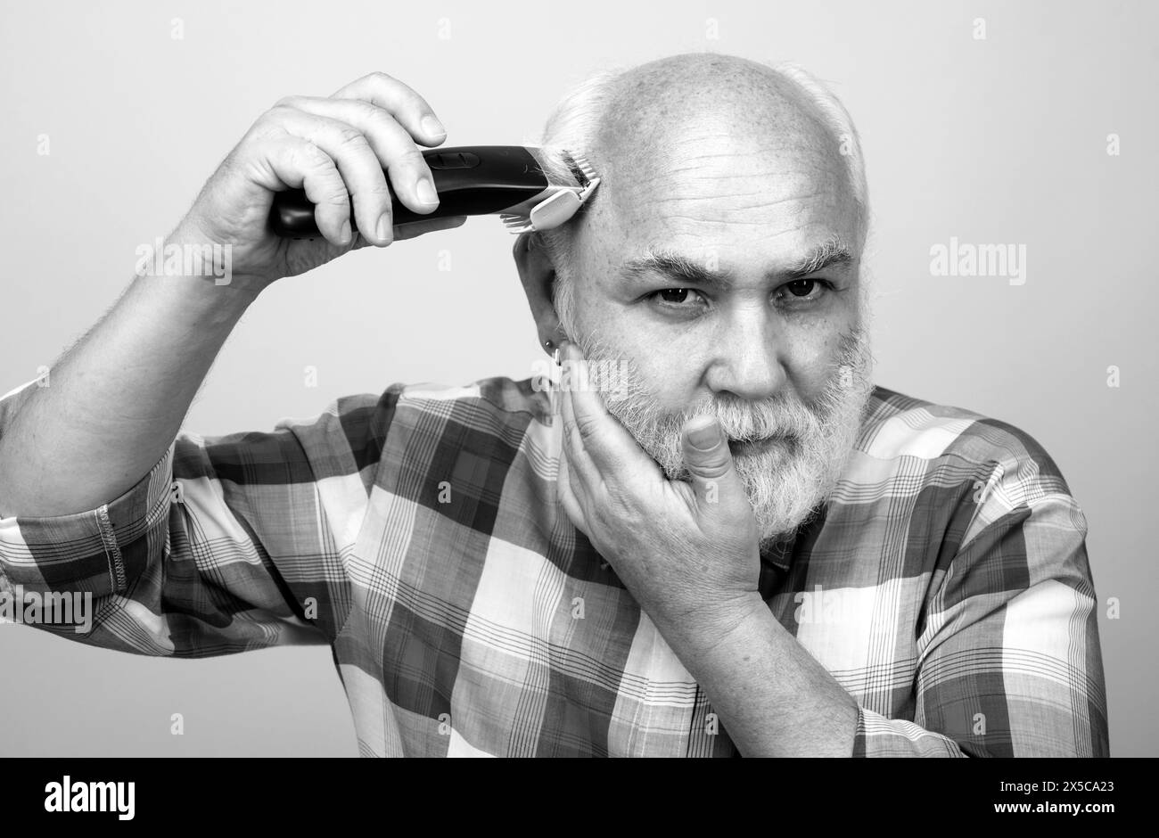 Senior hairdresser man with hair clipper, haircut with an electric ...