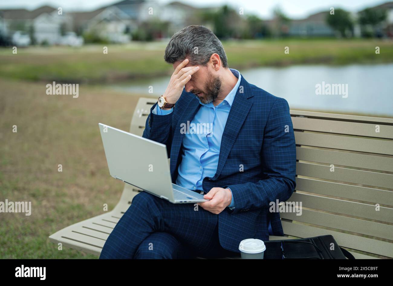 Stressed business man in suit sitting on bench. Stressed ceo manager work on laptop. Business ...