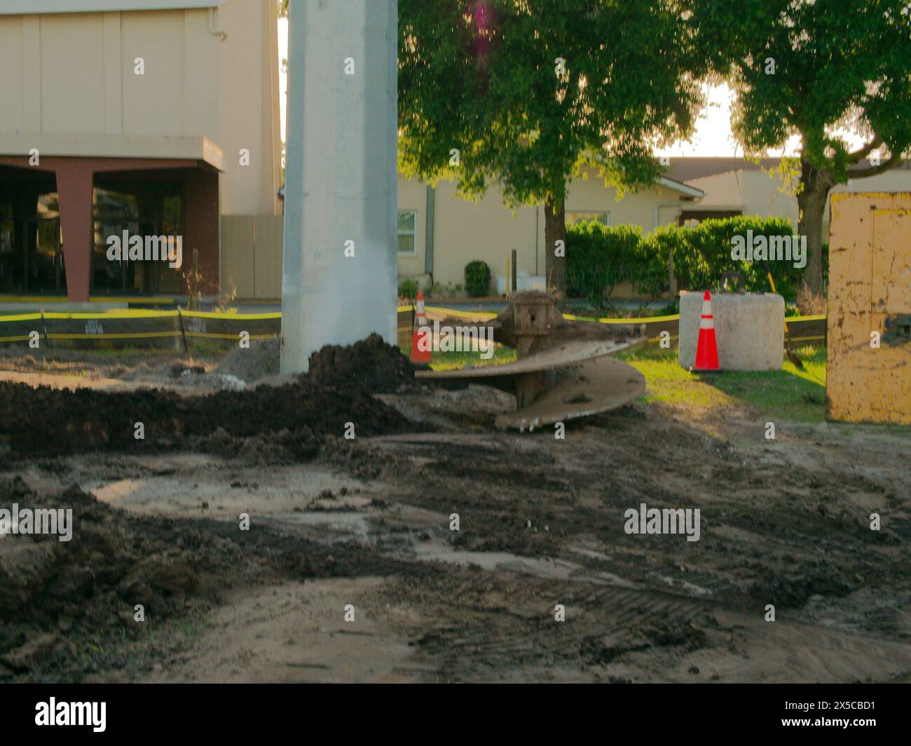 Wide view over dirt to a large Foundation Drill Auger Bit beside a ...