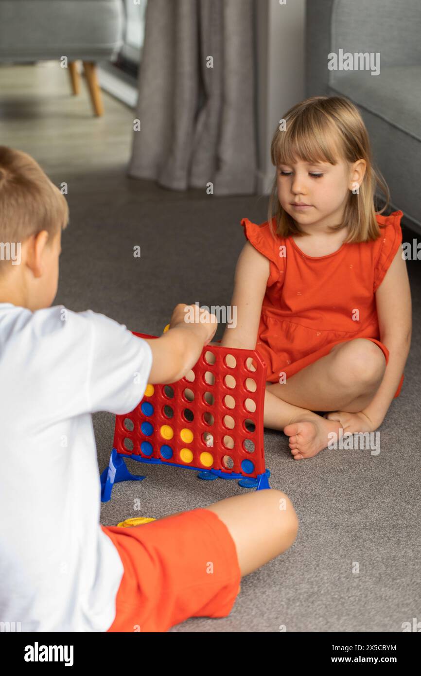 Siblings engrossed in a strategic board game, enhancing their logic ...