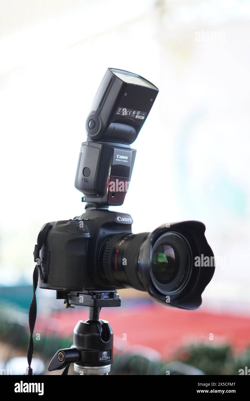 Black Canon DSLR camera mounted on a tripod with an external flash ...