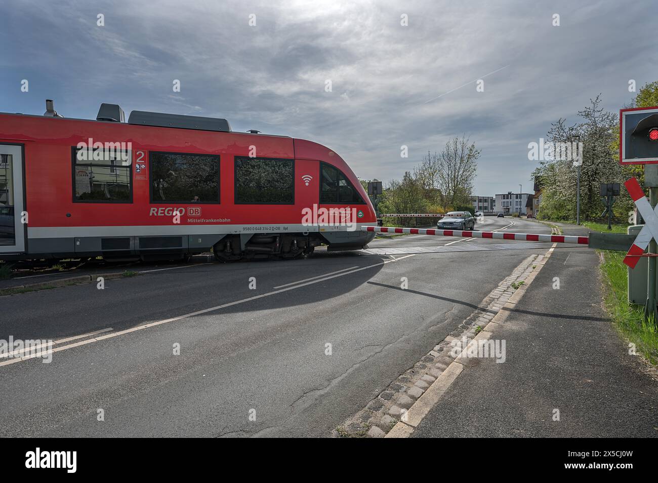 A regional train crosses a level crossing with a barrier, Schnaittach ...
