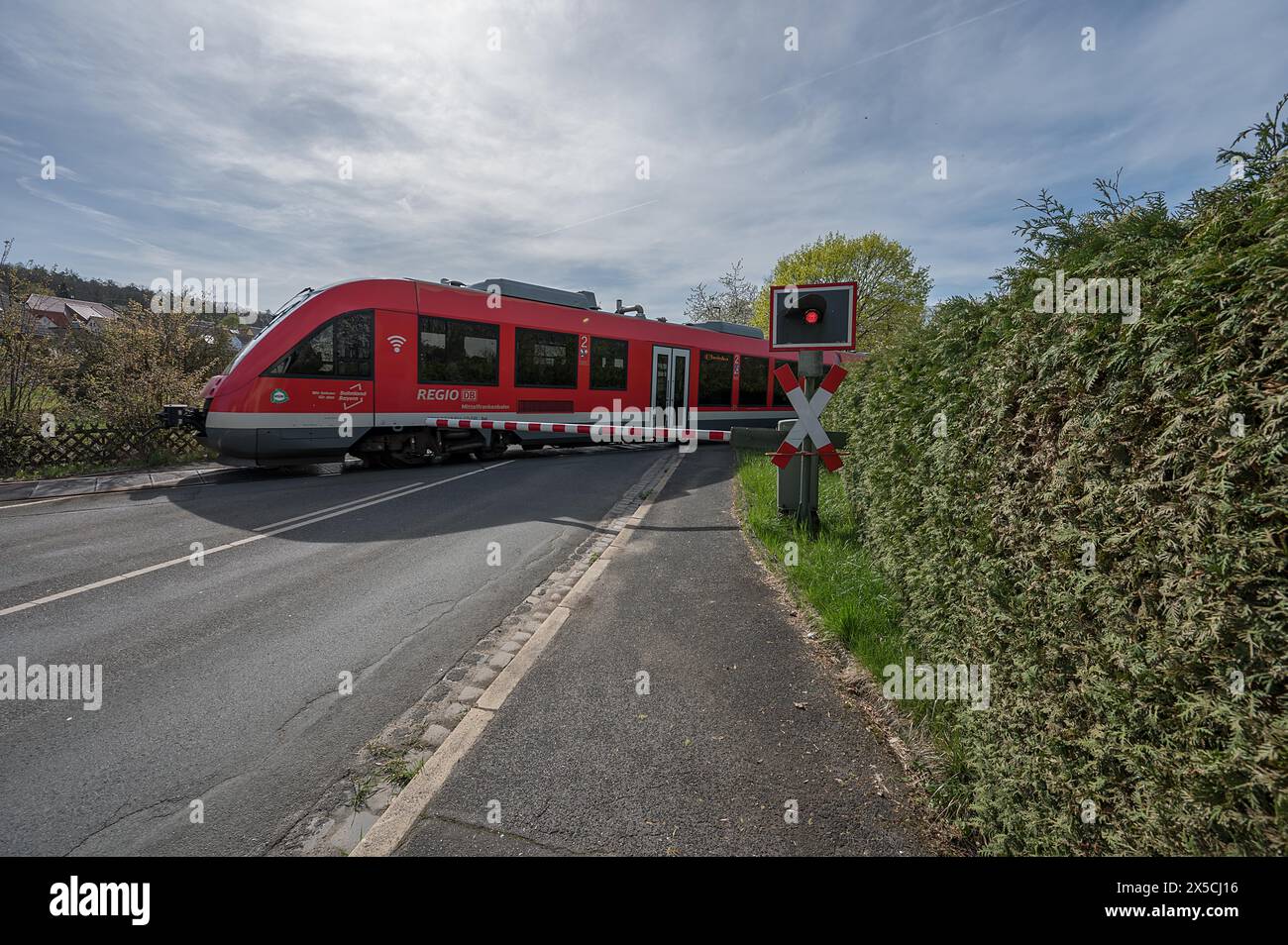 A regional train crosses a level crossing with a barrier, Schnaittach ...