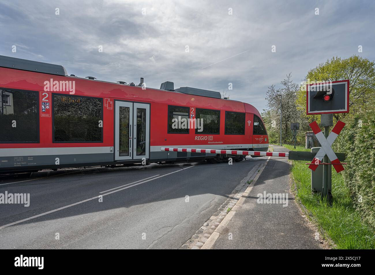 A regional train crosses a level crossing with a barrier, Schnaittach ...