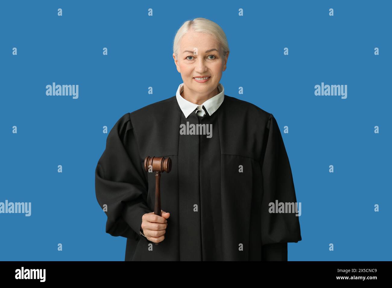 Mature female judge with gavel on blue background Stock Photo - Alamy