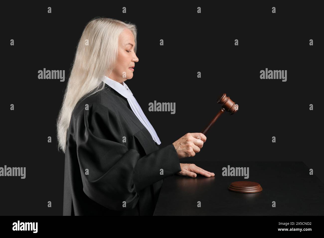 Mature female judge with gavel at table on black background Stock Photo ...