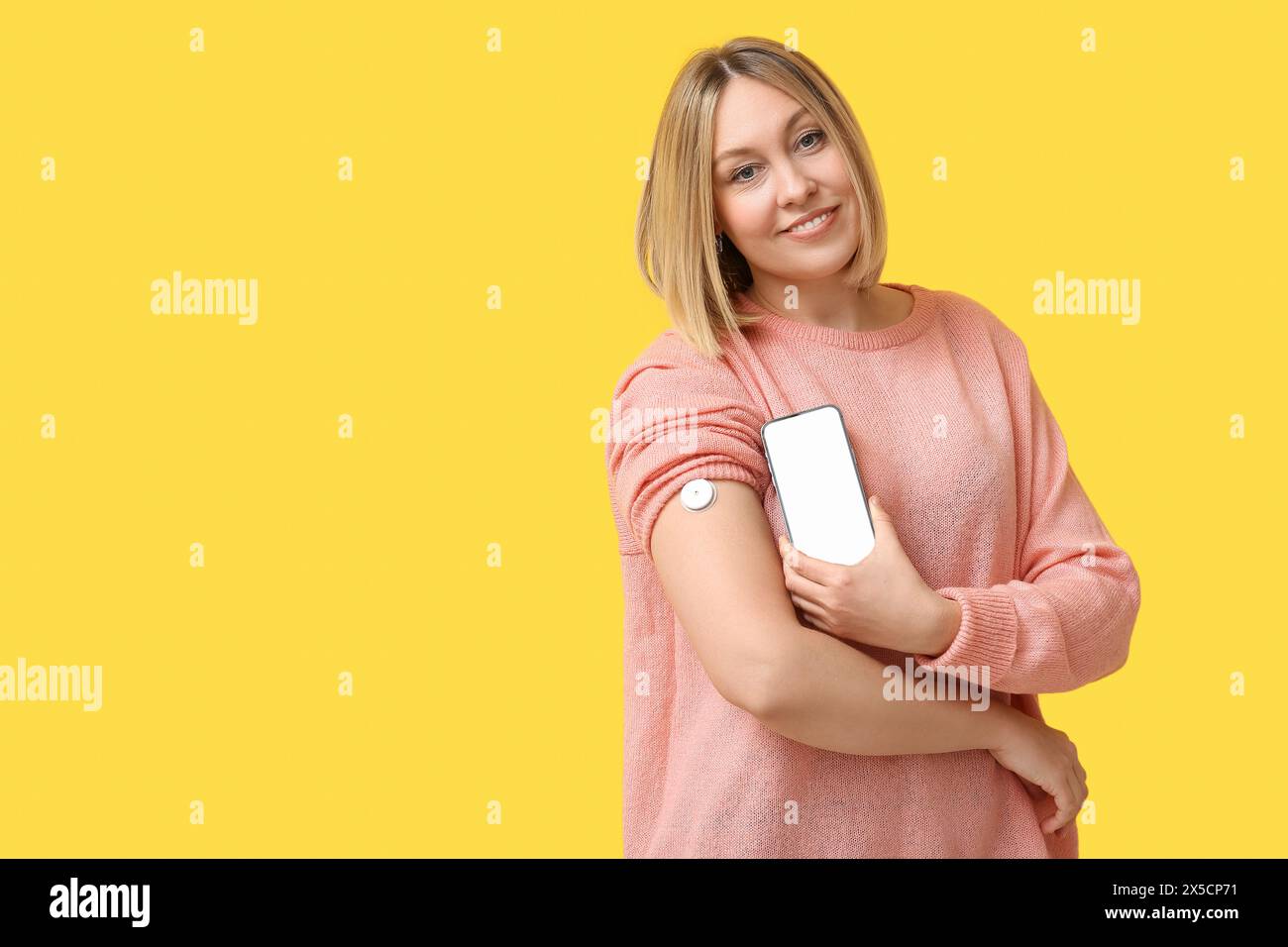 Woman with glucose sensor for measuring blood sugar level and phone on ...