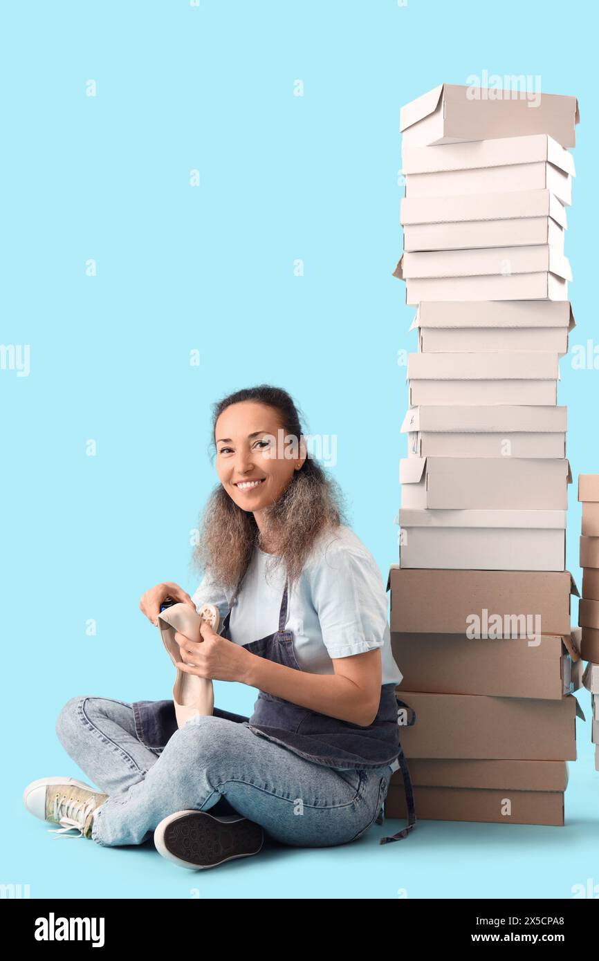 Female shoemaker with broken shoe and boxes sitting on blue background ...