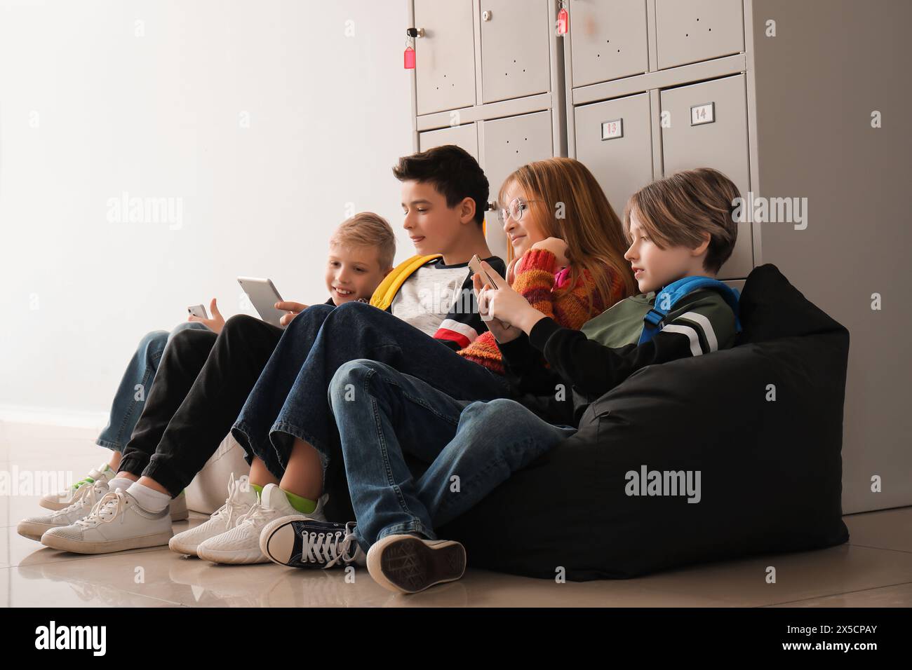 Little pupils using gadgets near locker at school Stock Photo - Alamy