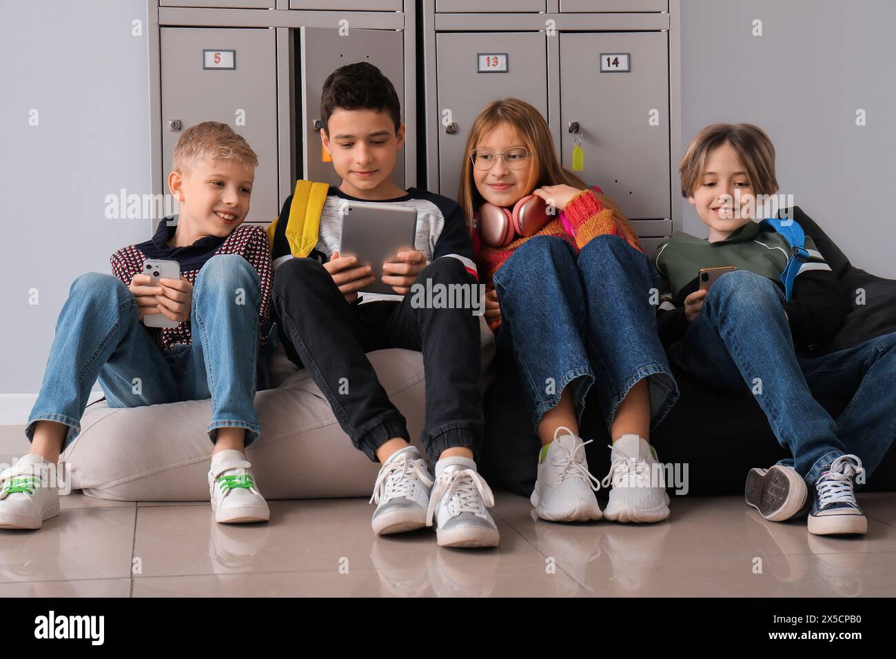 Little pupils using gadgets near locker at school Stock Photo - Alamy