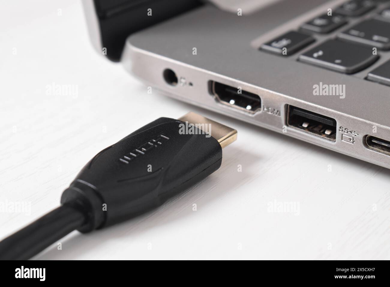 Man is connecting black HDMI cable into HDMI port of the modern laptop ...