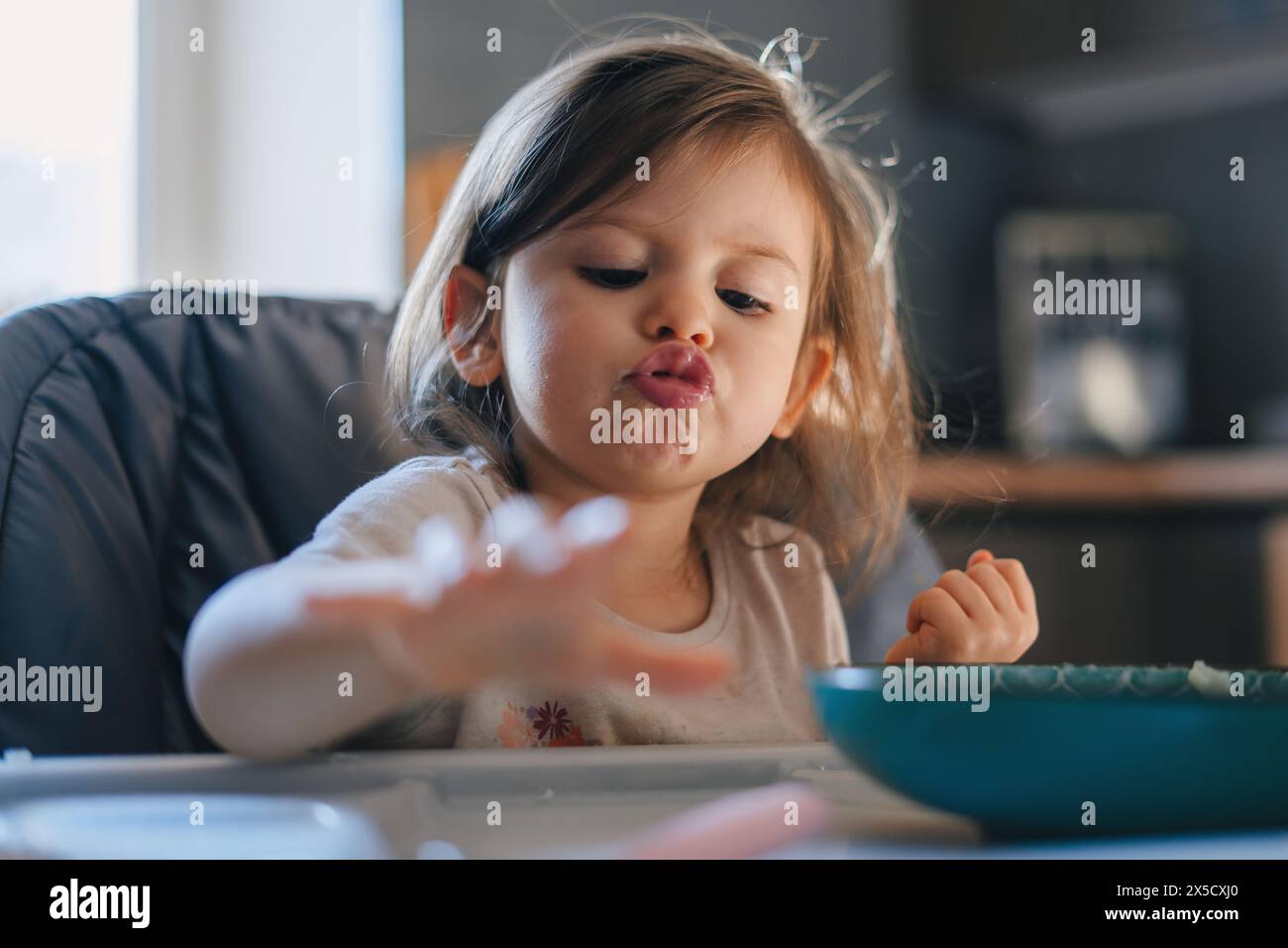Happy small cute kid girl eating morning meal from bowl feeling hungry ...