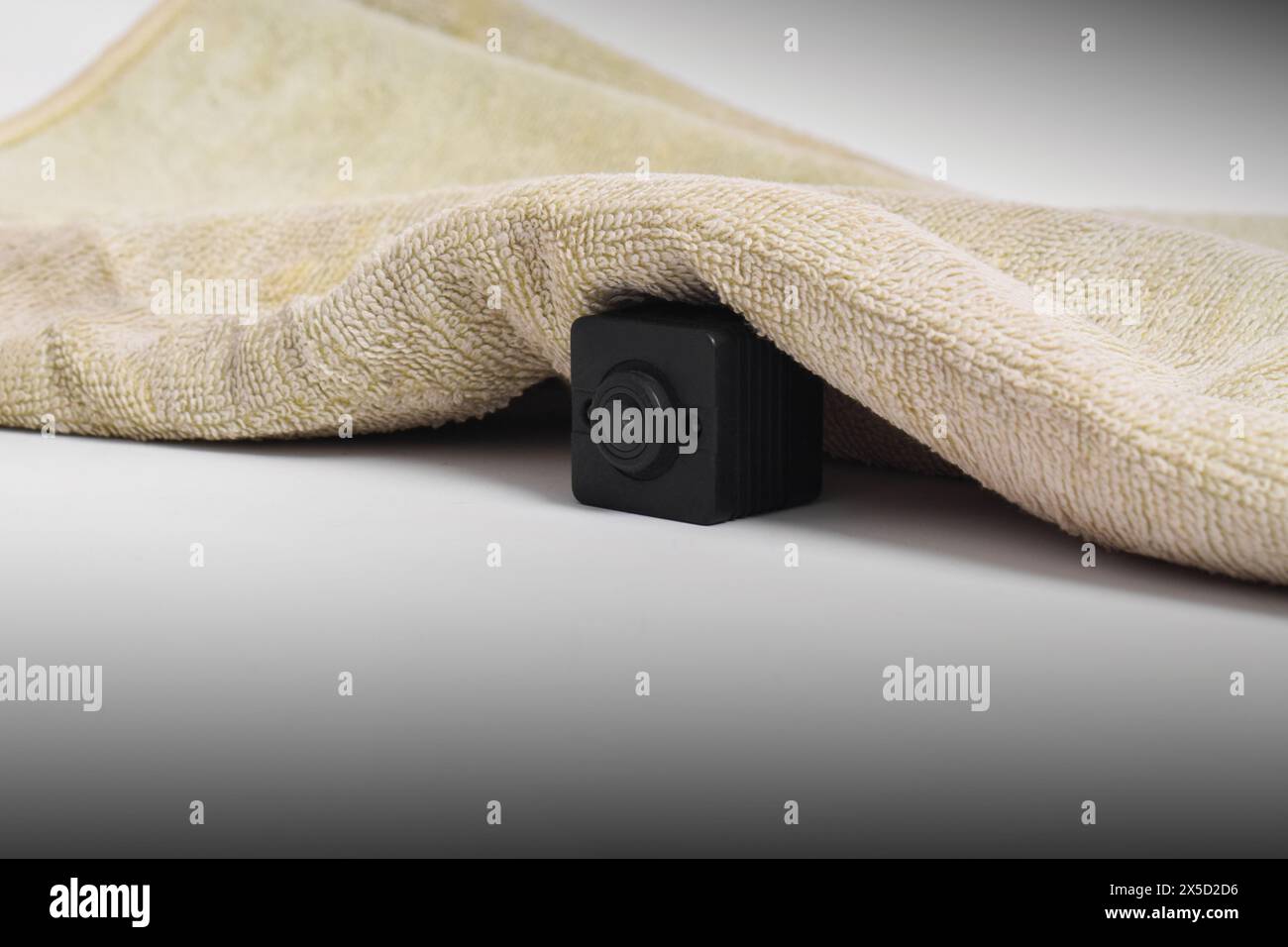 Closeup spy camera under cloth on white background. Black security ...
