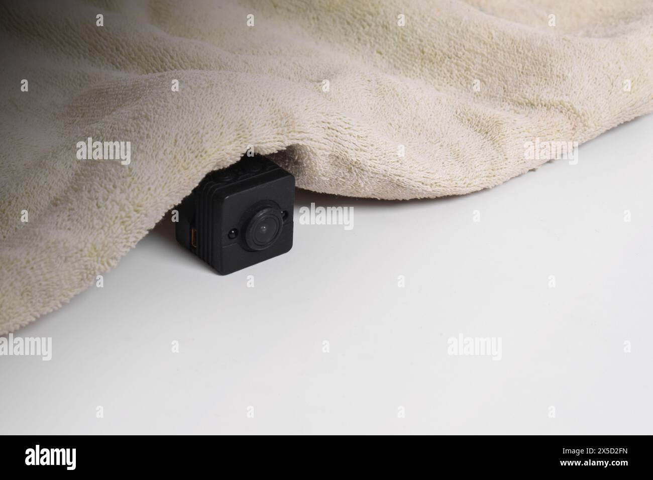 Closeup spy camera under cloth on white background. Black security ...