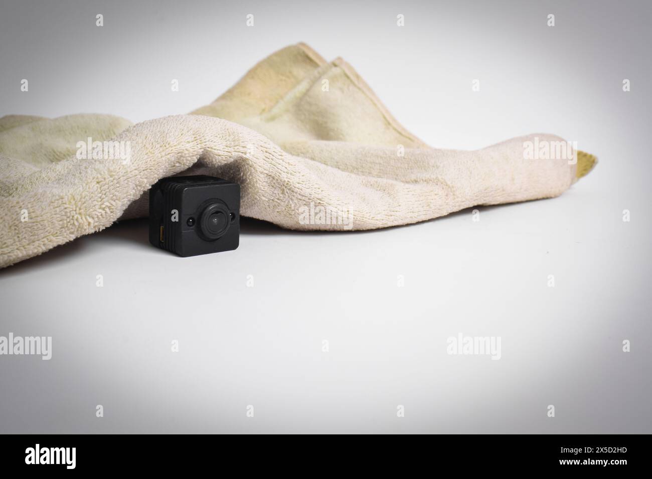 Closeup spy camera under cloth on white background. Black security ...