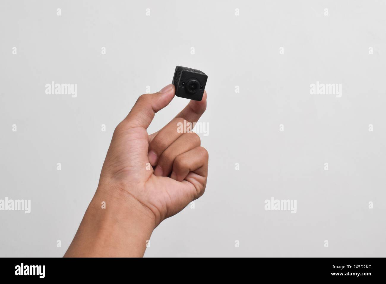 Hand holding a spy camera isolated on white background. Black security ...