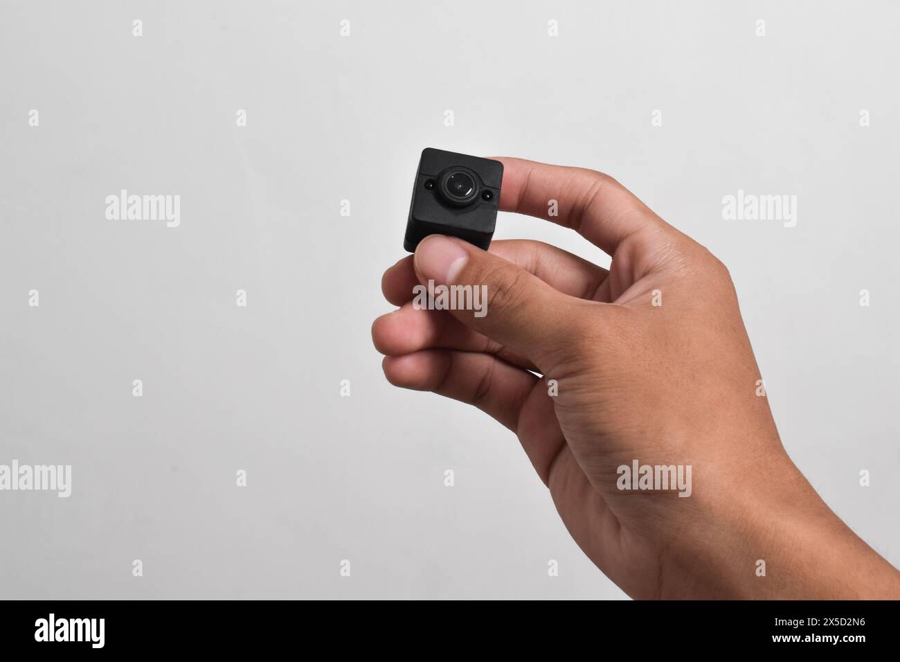 Hand holding a spy camera isolated on white background. Black security ...