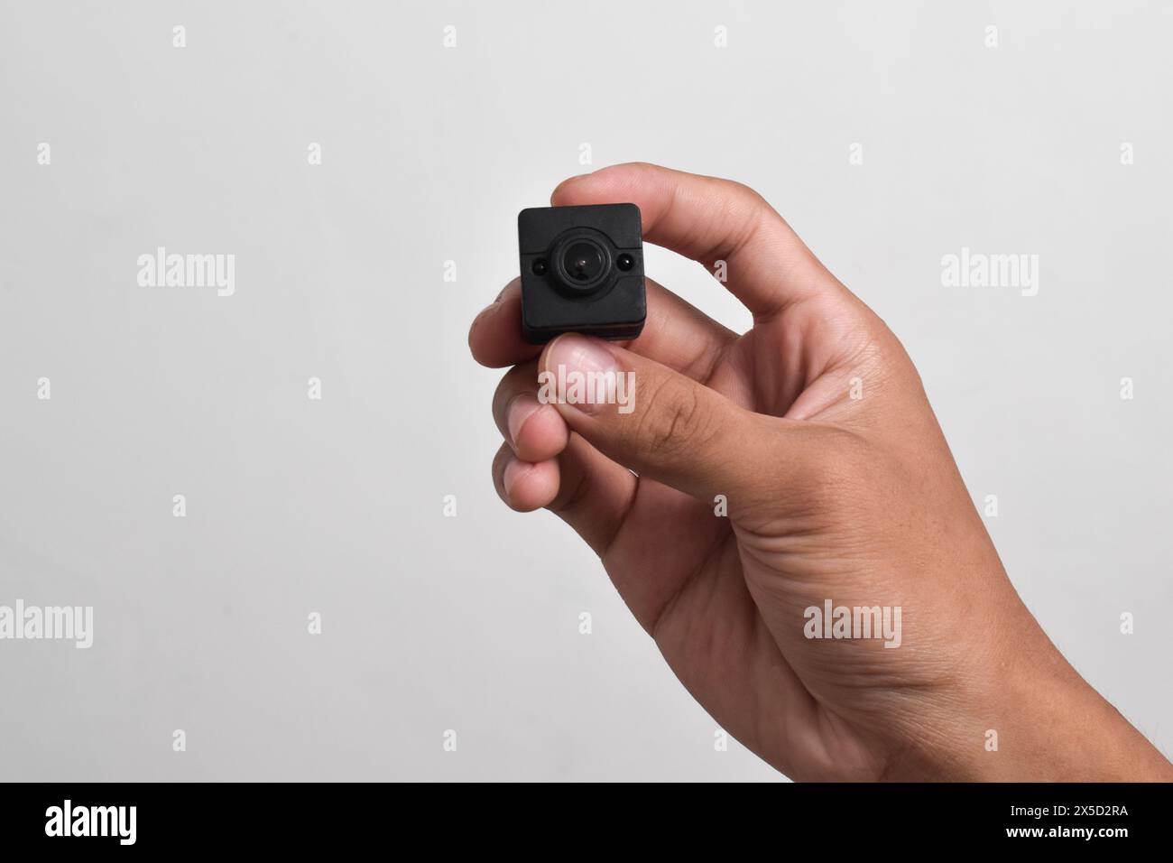 Hand holding a spy camera isolated on white background. Black security ...