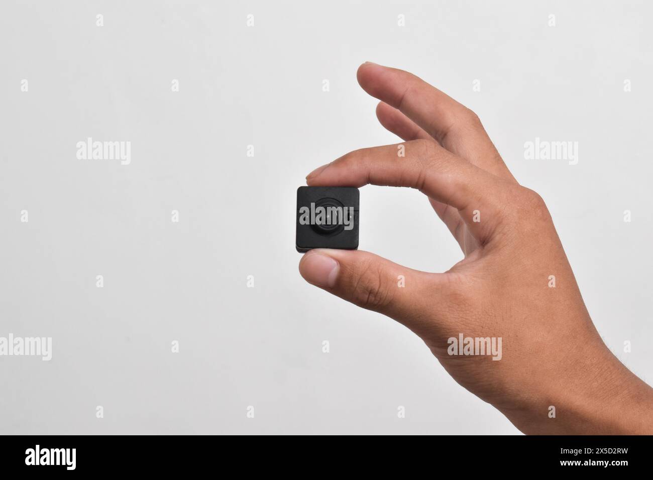 Hand holding a spy camera isolated on white background. Black security ...