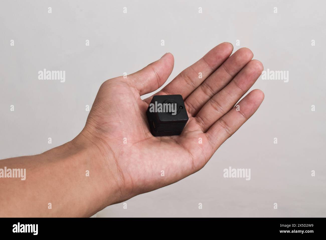 Hand holding a spy camera isolated on white background. Black security ...