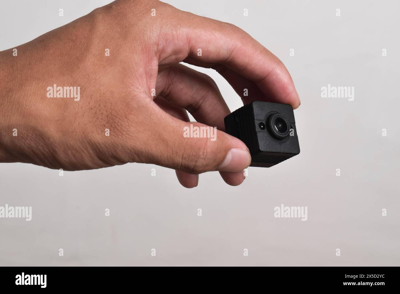 Hand holding a spy camera isolated on white background. Black security ...