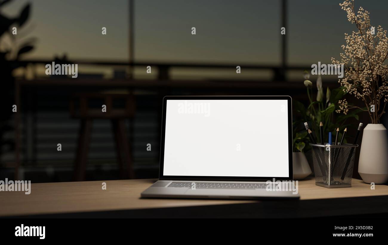 A laptop computer white-screen mockup on a wooden desk under dim light ...