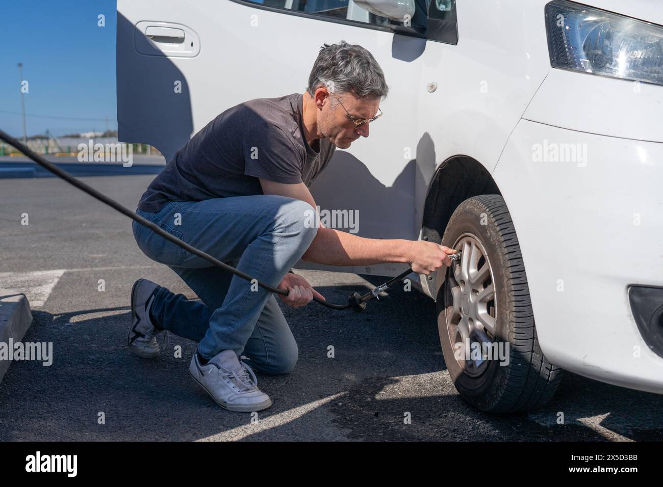 Caucasian man doing maintenance on his van before traveling, inflating ...